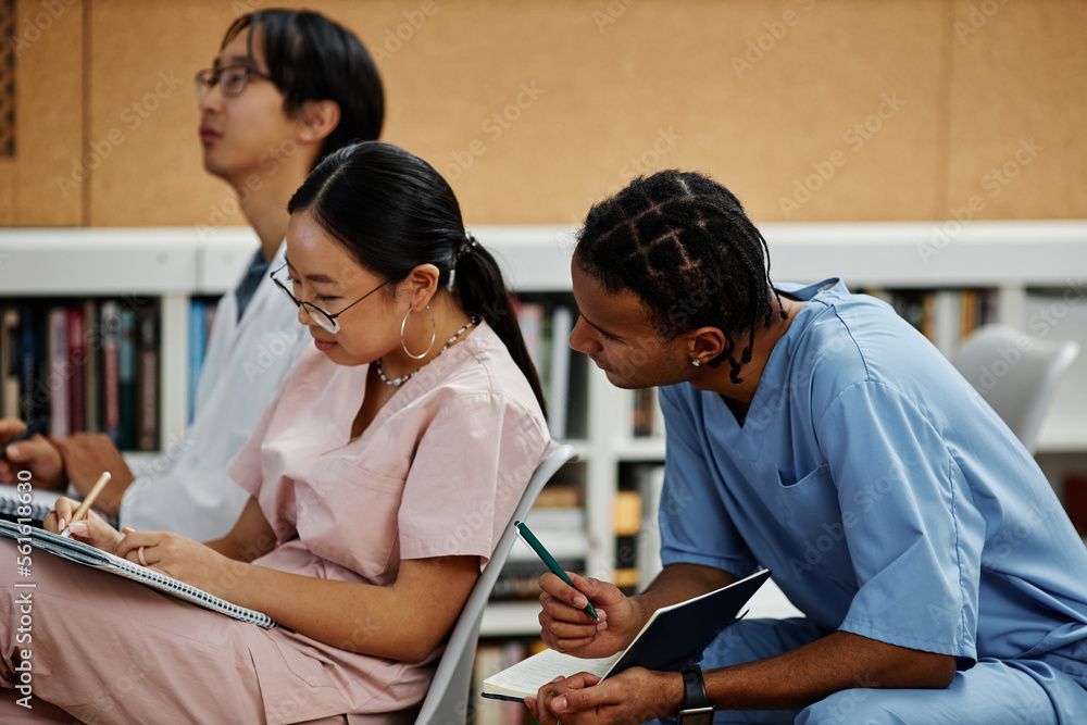 Side view portrait of two young med students talking in audience during ...