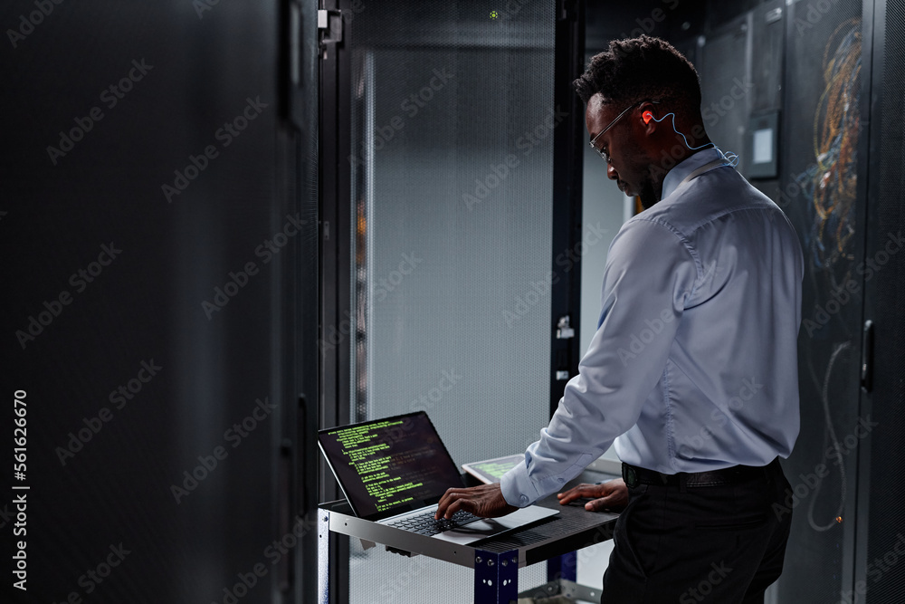 Side view portrait of black man as network engineer using laptop while ...