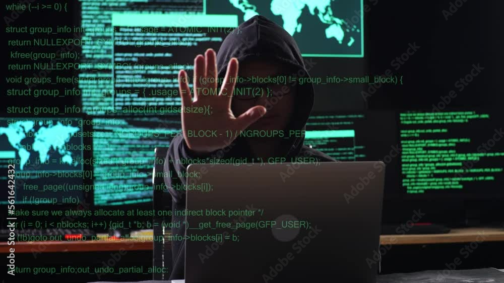 Asian Male Hacker In A Hood Showing Hand Palm To Camera While Works On ...
