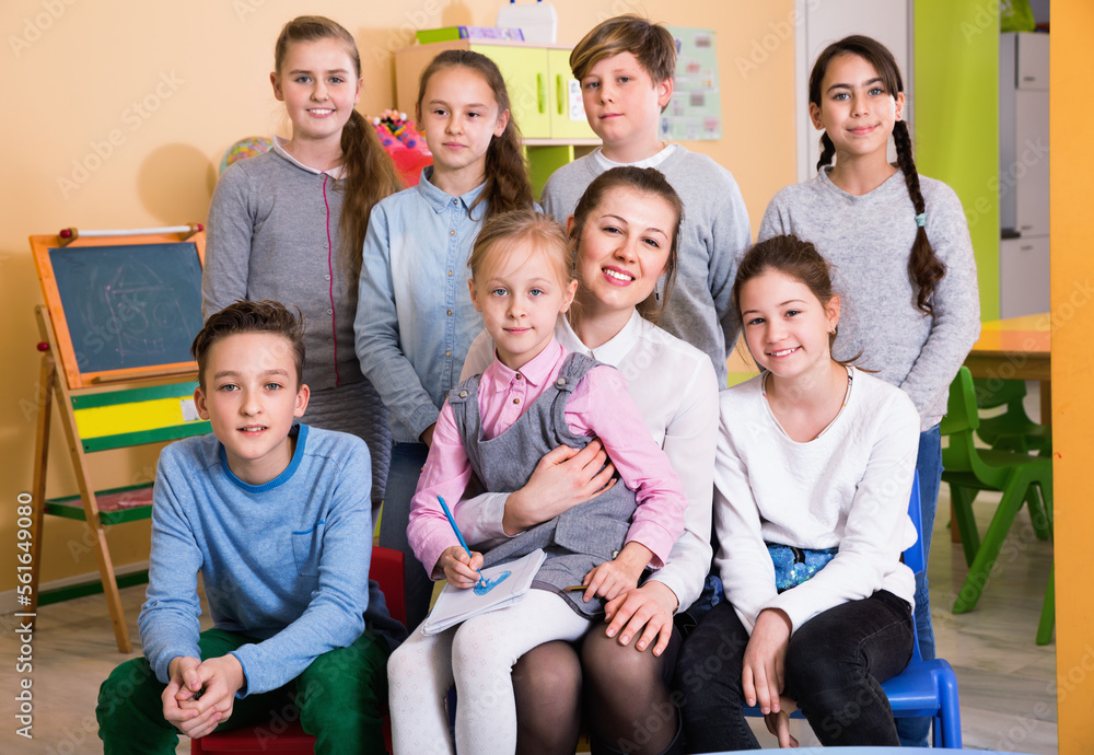Portrait of friendly positive group of pupils with female teacher ...