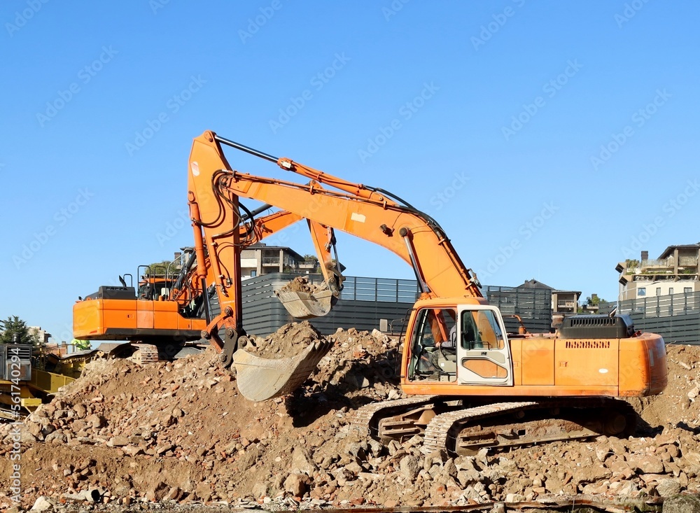 Two heavy excavators at work on a heap of dirt during urban ...