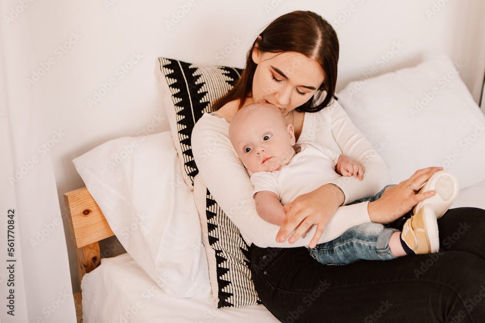 Little boy funny cute child baby, mother hold the child, lying on bed ...