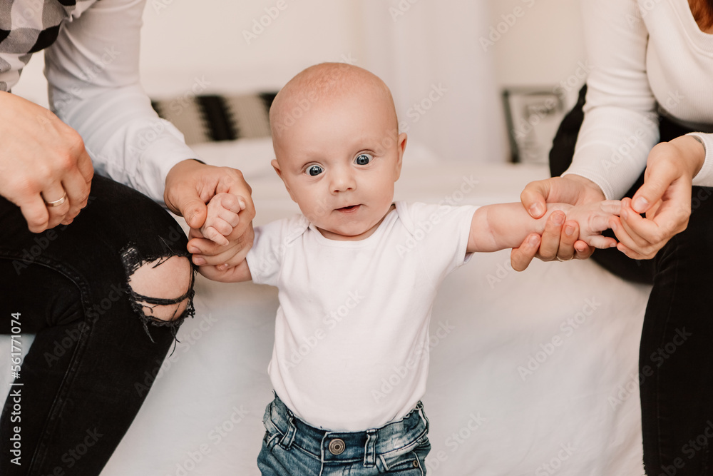 Little boy child baby playing with parents, standing learning to walk ...