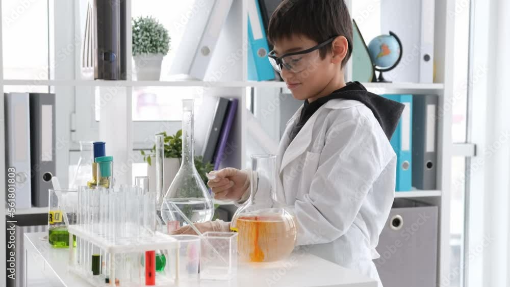 Schoolboy at chemistry lesson making experiment with orange chemical ...