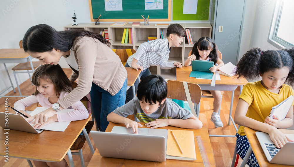 Pupil boy learn computer with teacher in classroom at elementary school ...