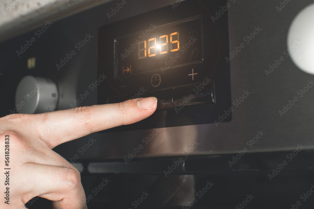 Woman is adjusting modern electric oven with timer for perfect food ...