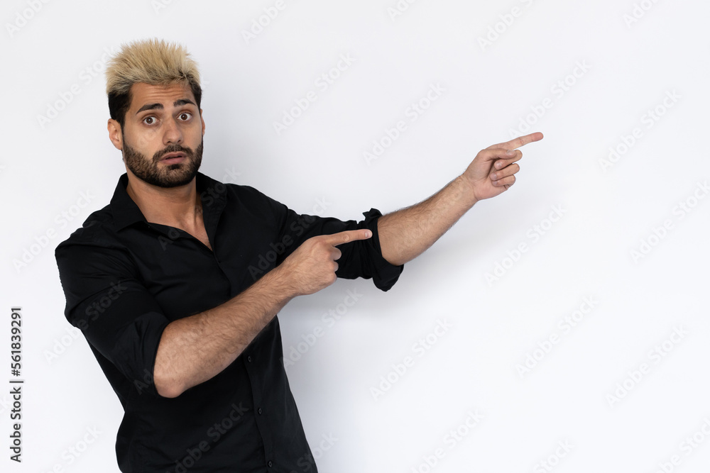 Astonished young man pointing with fingers at copyspace. Male Caucasian ...