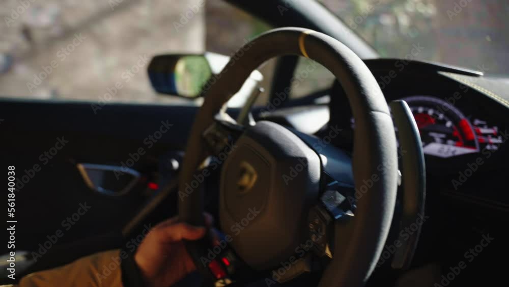 Unrecognisable driver steering wheel of sports car with powerful motor ...