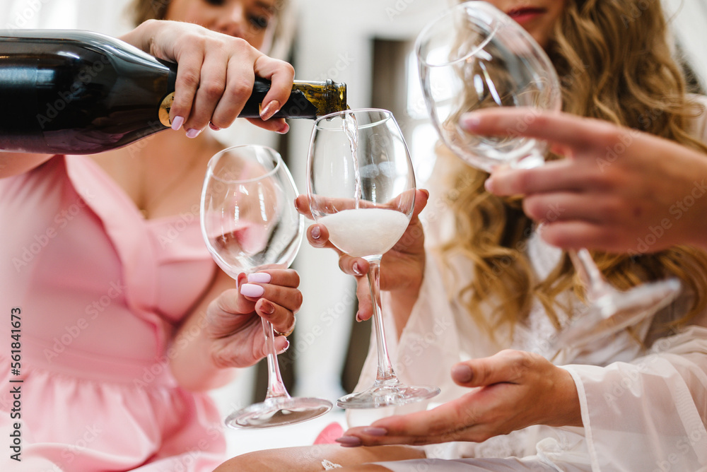 Pour white wine. Bride and bridesmaids toasting with champagne and ...