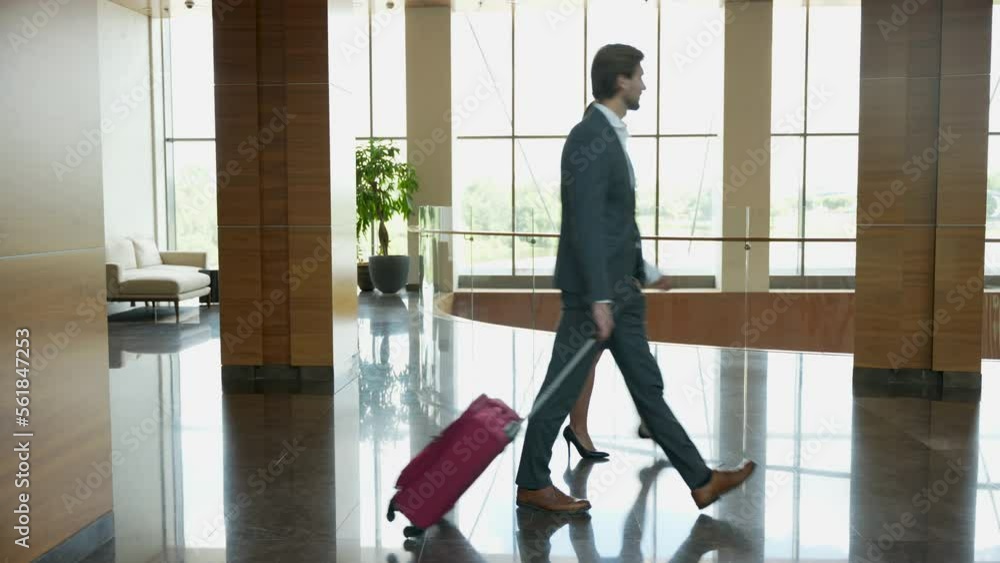 Two business people walking at hotel corridor, arriving in hotel for ...