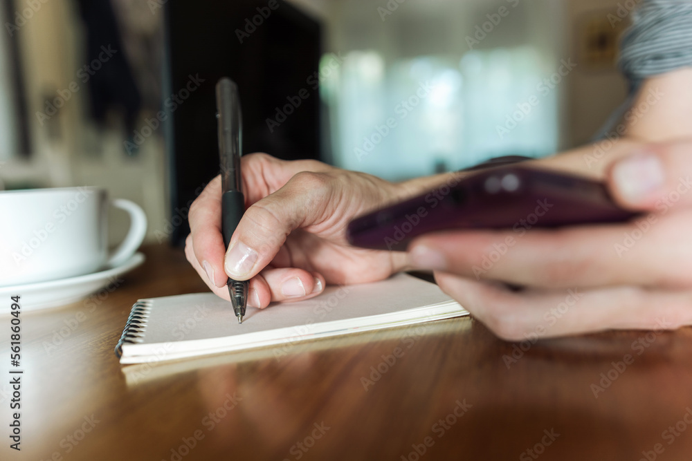 Hand holding mobile phone while writing a notes in home office Stock ...