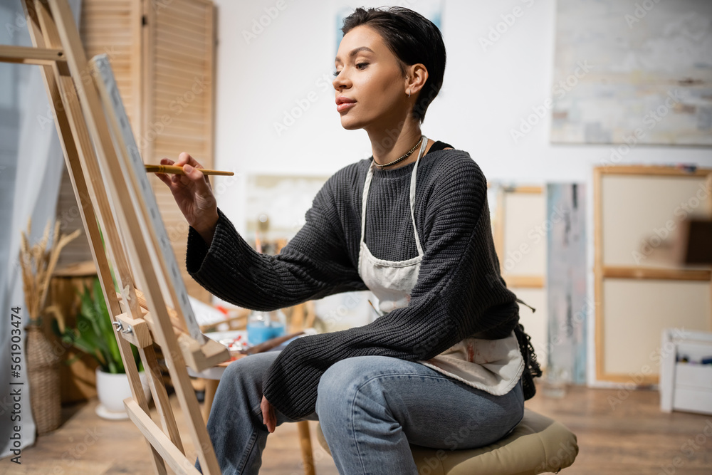 Short haired artist sitting and painting on canvas in studio Stock ...