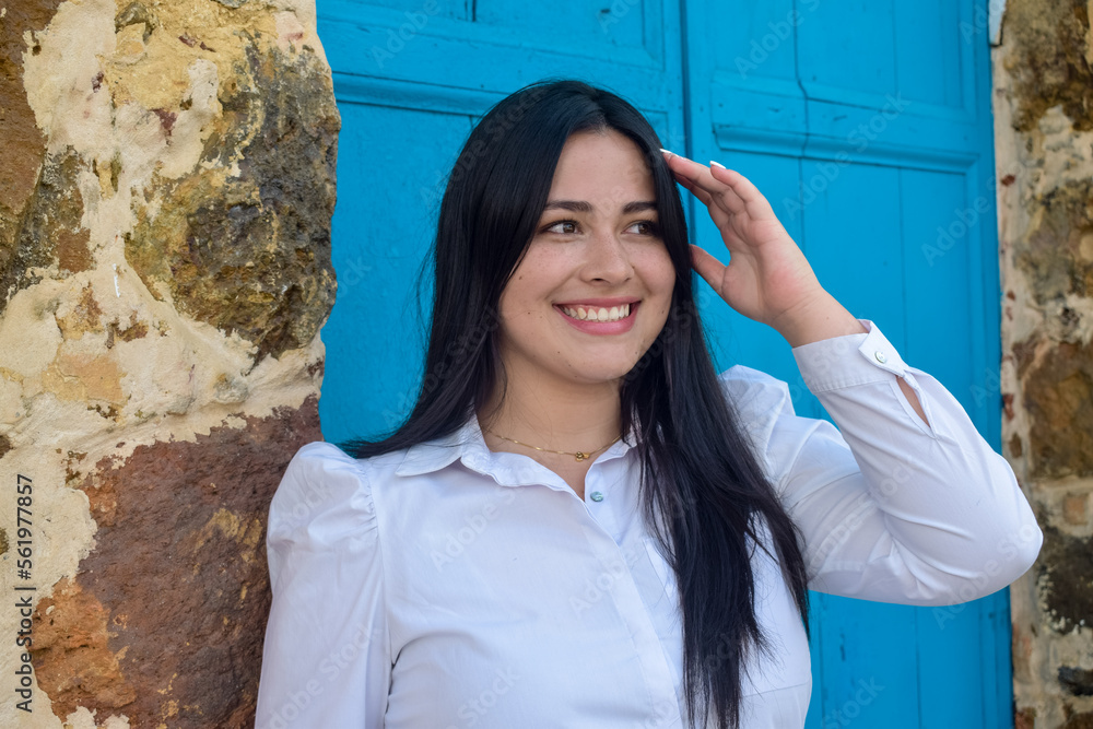 chica pelinegra con blusa blanca sonriente con un muro de sillares de ...