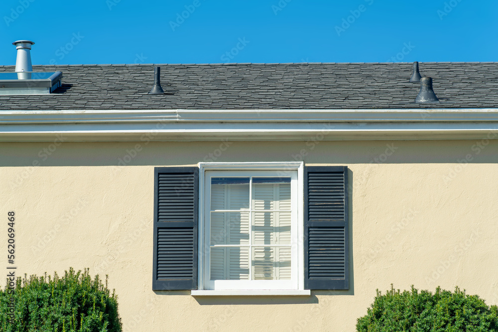 Lone window on beige house facade with green shutters and white accent ...