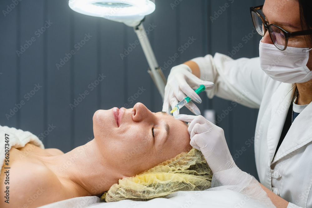 Beautician apply skin injections in woman forehead Stock Photo | Adobe ...