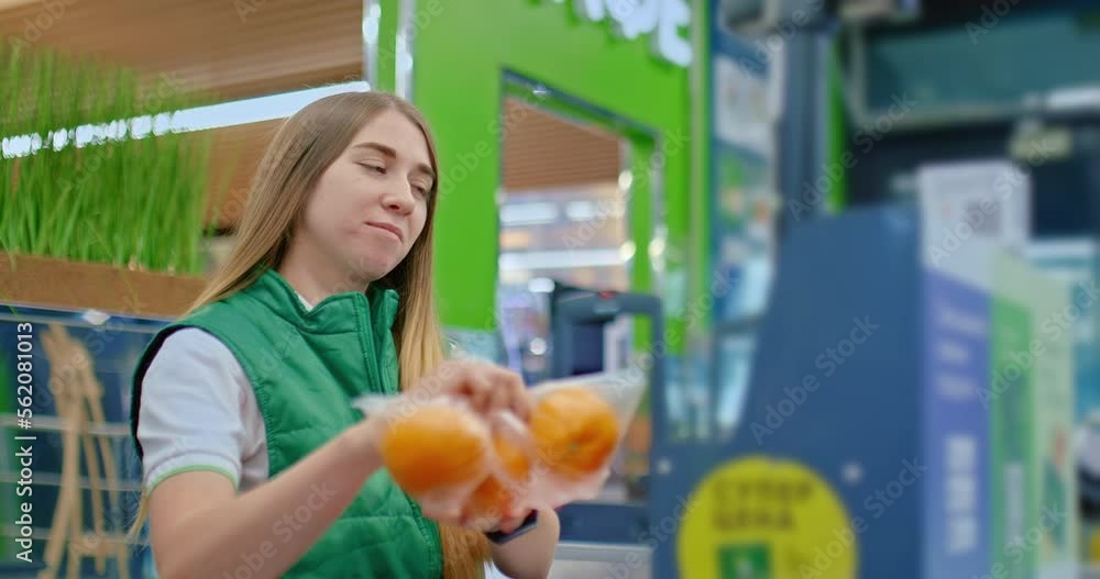 female cashier of supermarket scanning barcodes of goods at counter ...