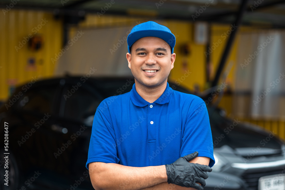 Man worker in uniform washing standing front car service station. Car ...
