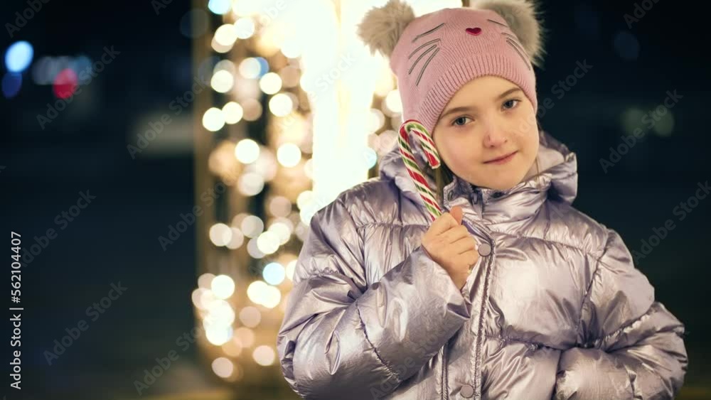 Portrait happy cute girl with lollipop candy standing in street of cold ...