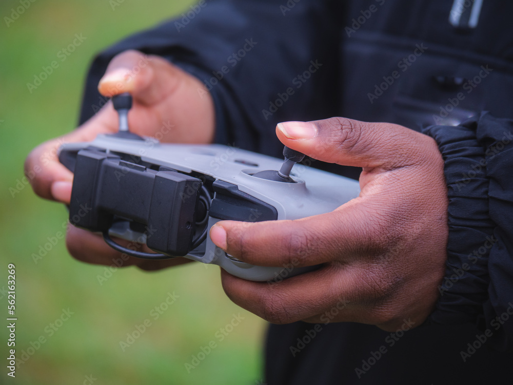 handsof young african person standing flying drone outdoors in a park ...