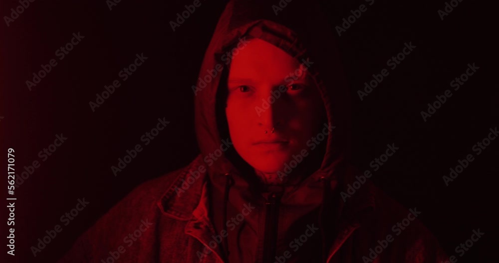 Portrait of young man walking at night taking off hood and looking at ...