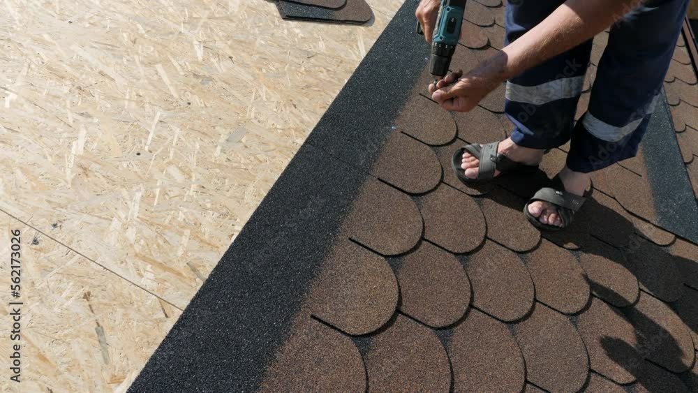 Installation of a soft roof on a sheet of OSB. The master roofer screws ...