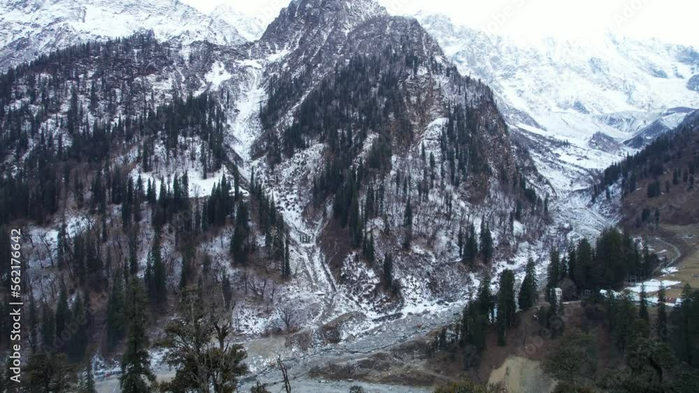 take off aerial drone shot snow covered mountains with pine trees on ...