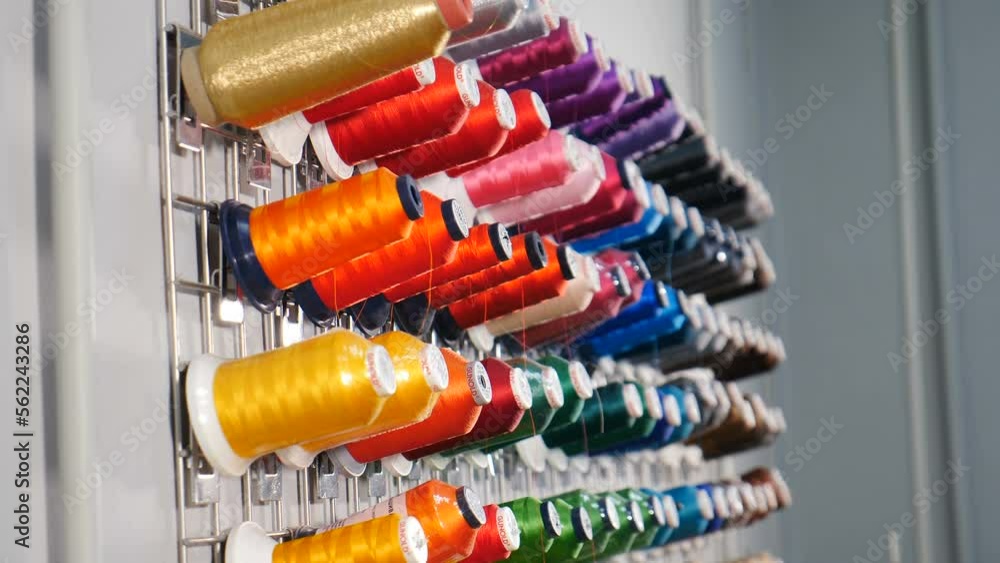 Rows spools of thread of different colors in industrial sewing factory ...