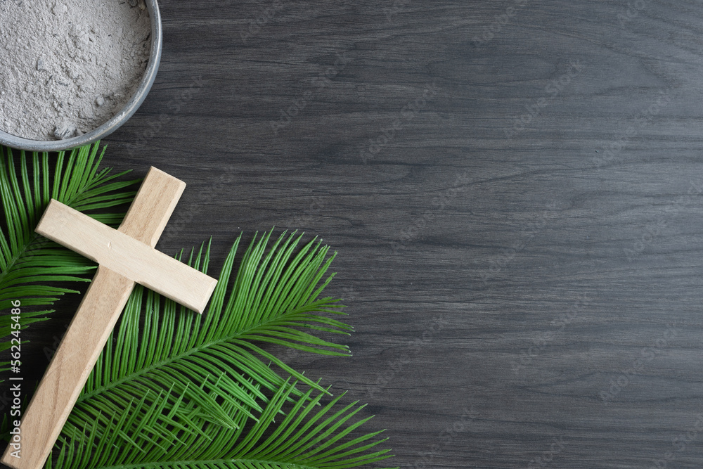 Border of small wood cross, palm leaves and bowl of ashes on a dark ...