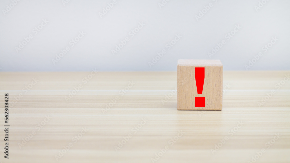 Warning exclamation mark on a wooden block to attract attention over a ...