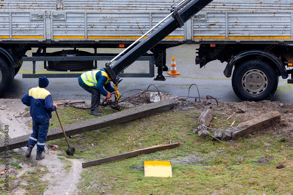 Utility workers remove a fallen electric pole after a car accident ...