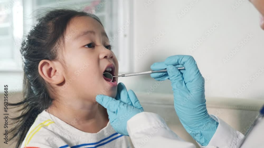 Dental kid health examination. Asian dentist making examination procedure for cute little girl ...