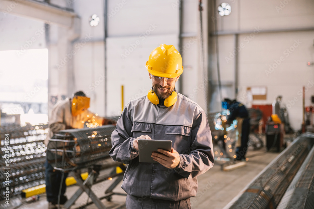 A happy metallurgy supervisor is doing checklist in facility while ...