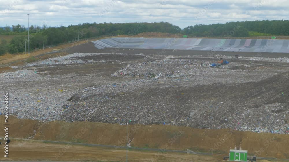 Garbage truck works on trash dump landfill site with waste materials ...