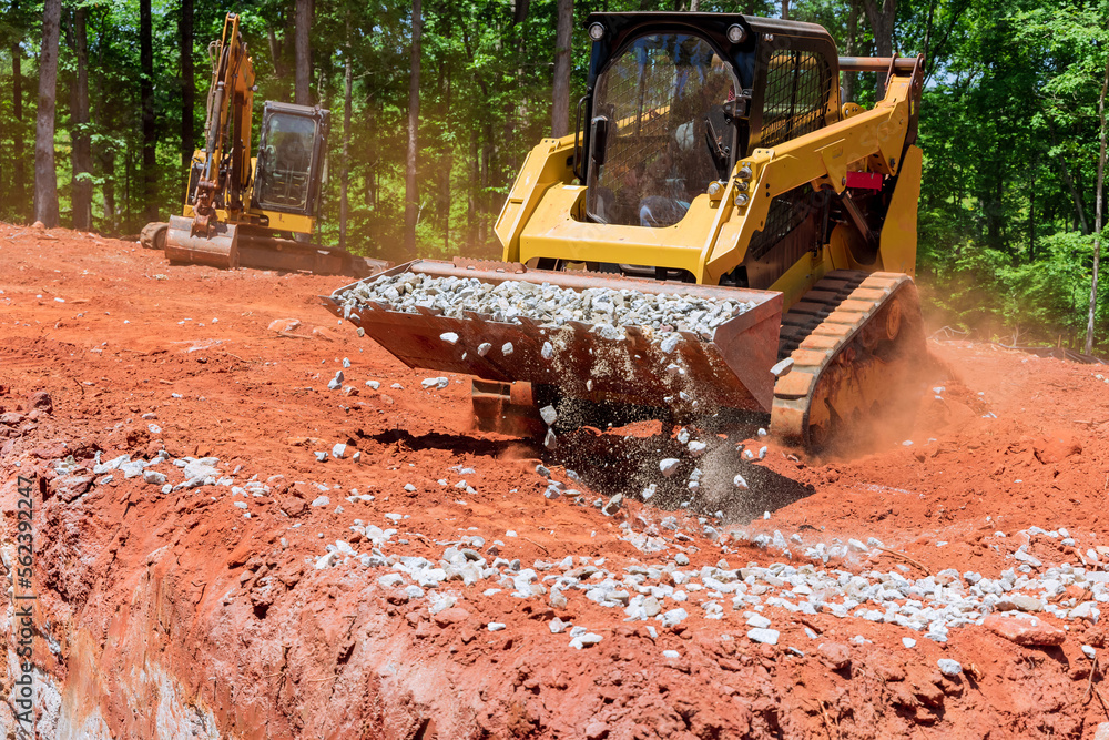 An excavator bucket rakes in crushed stone the excavator is picking up ...