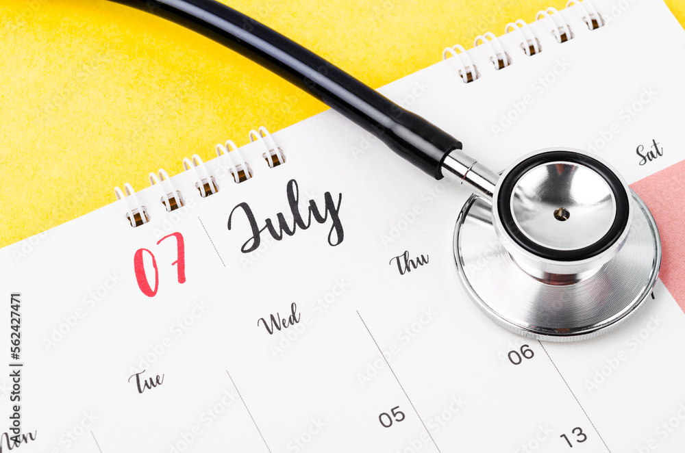 The July 2023 deskcalendar and medical stethoscope medical on yellow ...