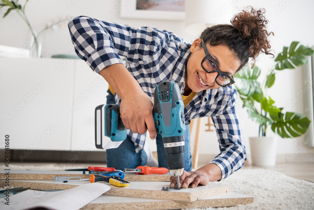 Black woman holding electric drill tool to assembly furniture in new ...