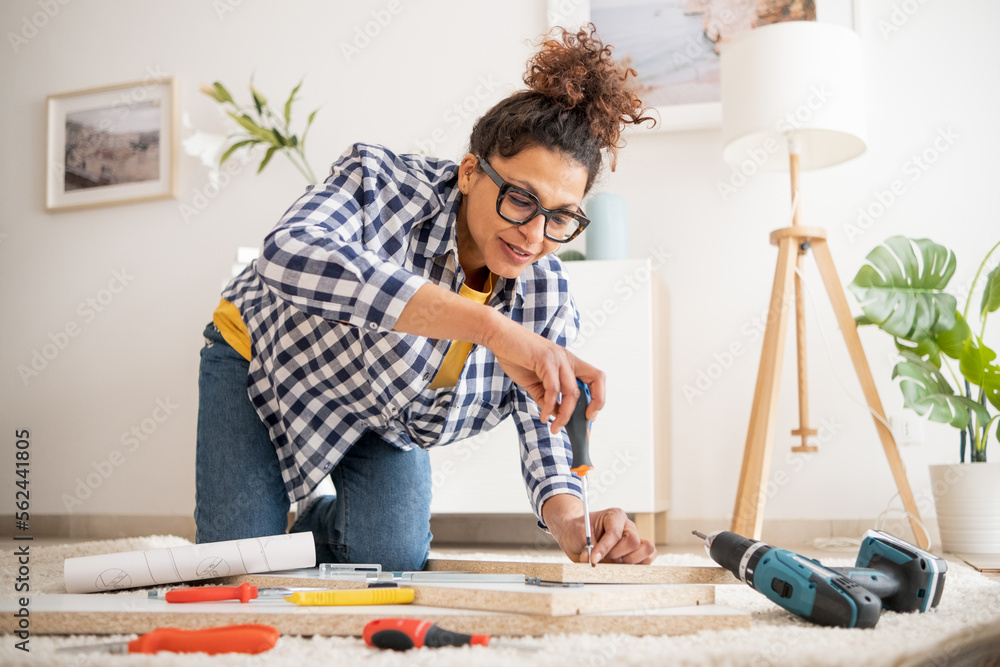 Black woman holding electric drill tool to assembly furniture in new ...