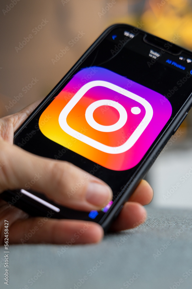 Hand holding a smartphone with an Instagram icon on screen. IPhone with ...