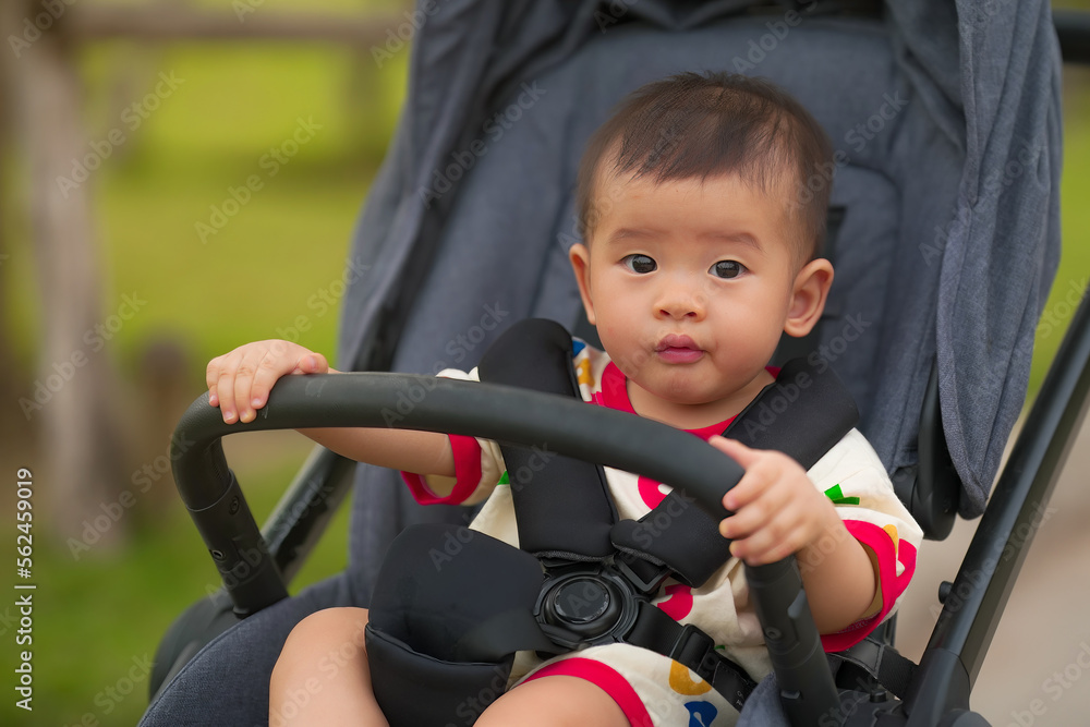 A small child sits in a stroller on the street in the park and waits ...