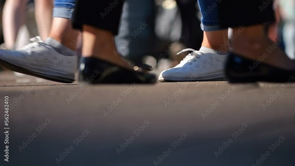 Legs of a crowd of people walking down the street, close-up of people's ...
