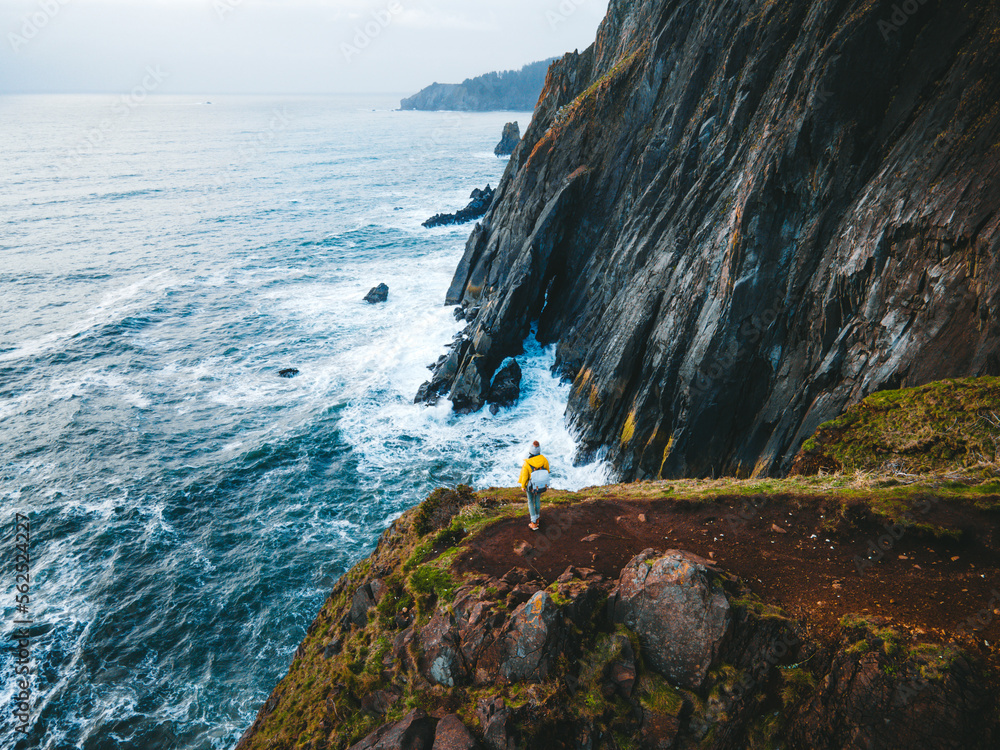 Drone view of ocean waves and a girl standing near the cliff on Elk ...