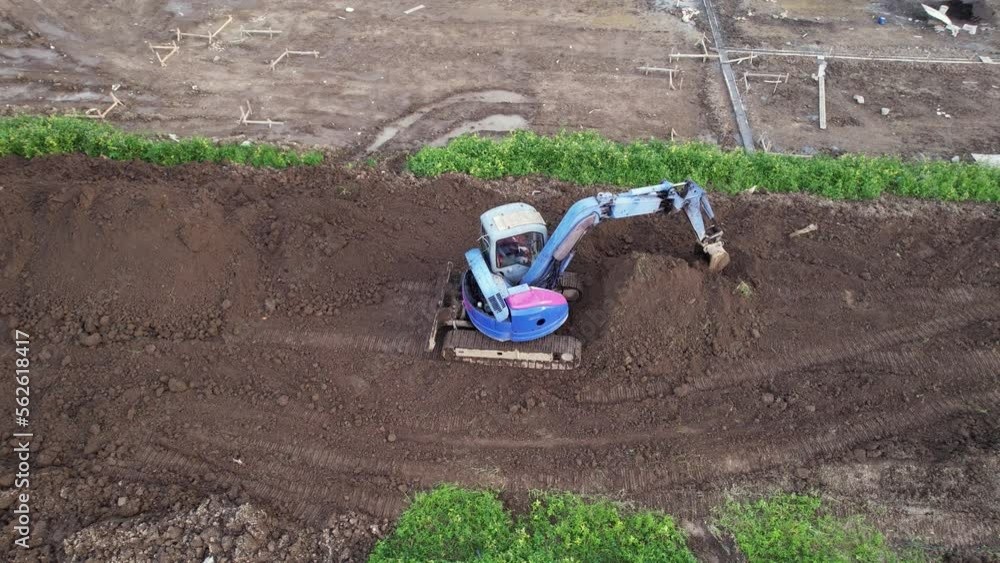Small excavator take earth from heap, turn around and dump out from ...