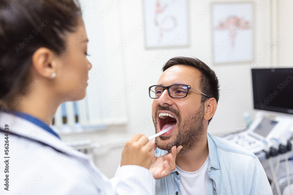 Male patient opening his mouth for the doctor to look at his throat ...