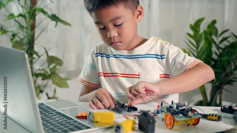 Asian kid boy plugging energy and signal cable to sensor chip with ...