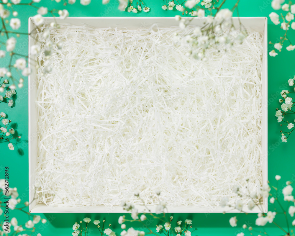 Opened gift box with shredded paper with white flowers. White paper box ...
