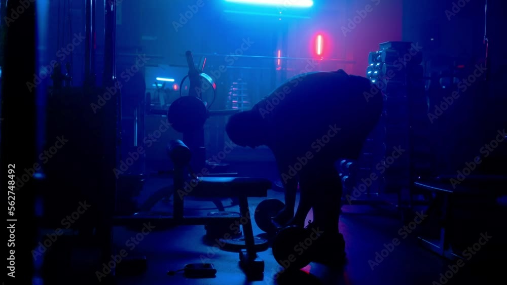 Side view of dark silhouette of bodybuilder pumping his arms with ...