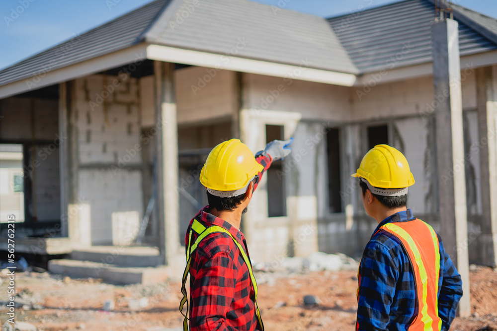 Male construction workers joining hands to build a house in the construction site. Stock Photo ...