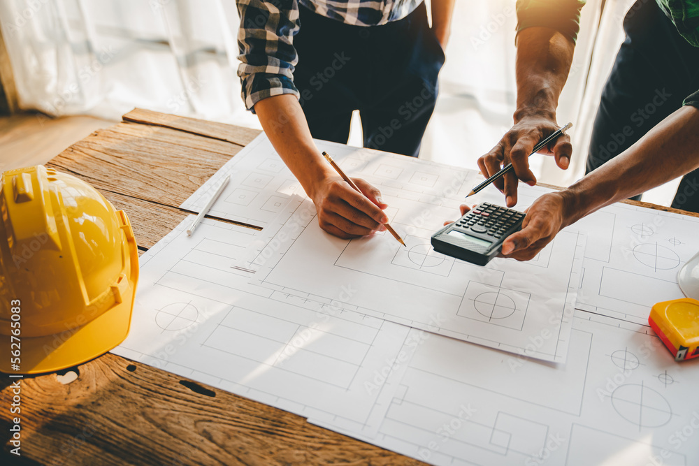 Engineers work as a team with blueprints for architectural plans ...