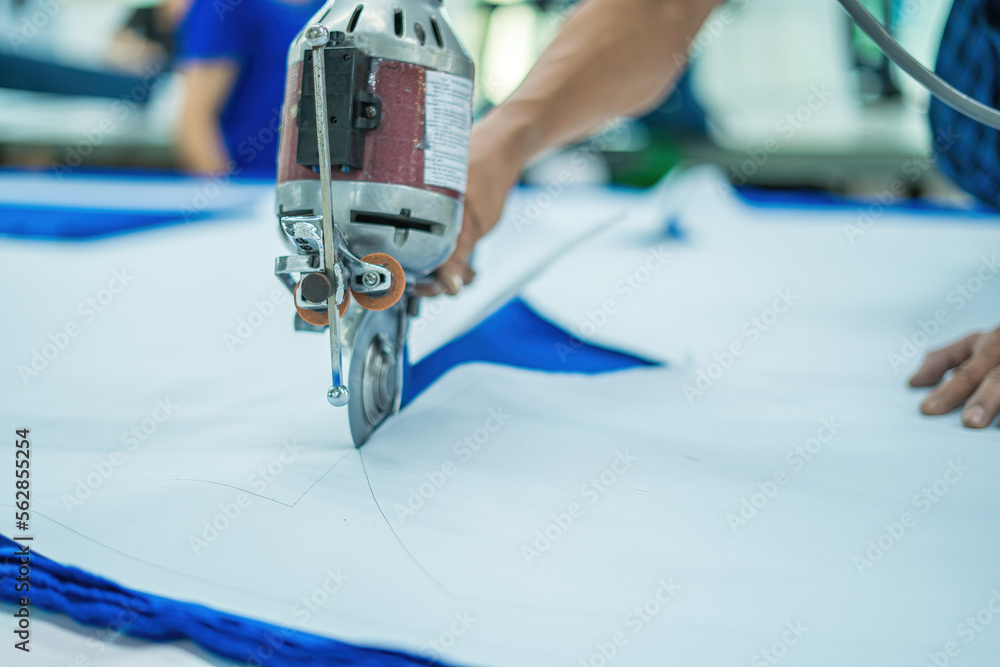 Man with cutter machine and personal protective equipment at garment ...