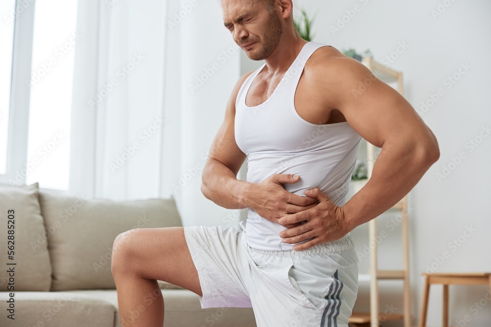 Man sports pain in the side and leg during a workout at home, pumped up ...